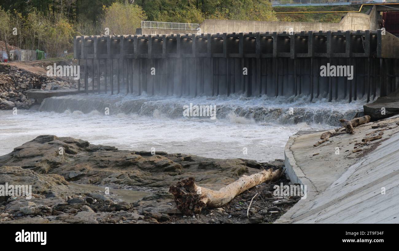 a dam with a powerful flow of water, a view from the shore with ...