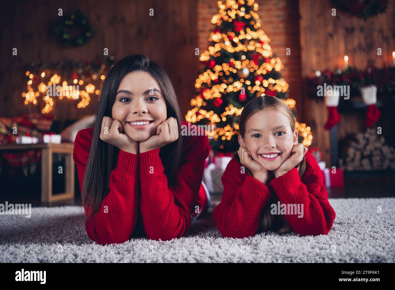 Photo of shiny adorable small sisters wear red jumpers smiling lying ...