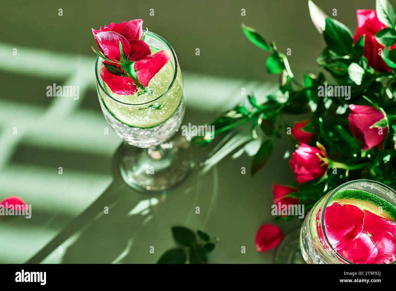 Delicious refreshing champagne drink with lemon and roses on green ...