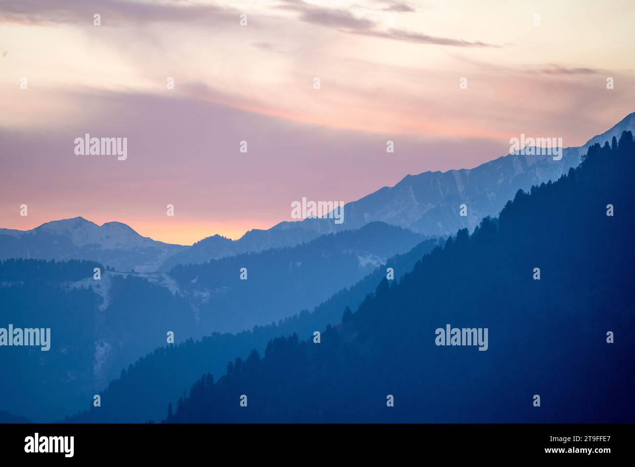 Pink blue hues of himalaya mountains fading off into fog showing the ...