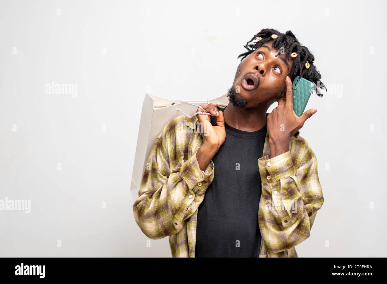 Black Friday, young black guy using smartphone and holding shopping bag ...