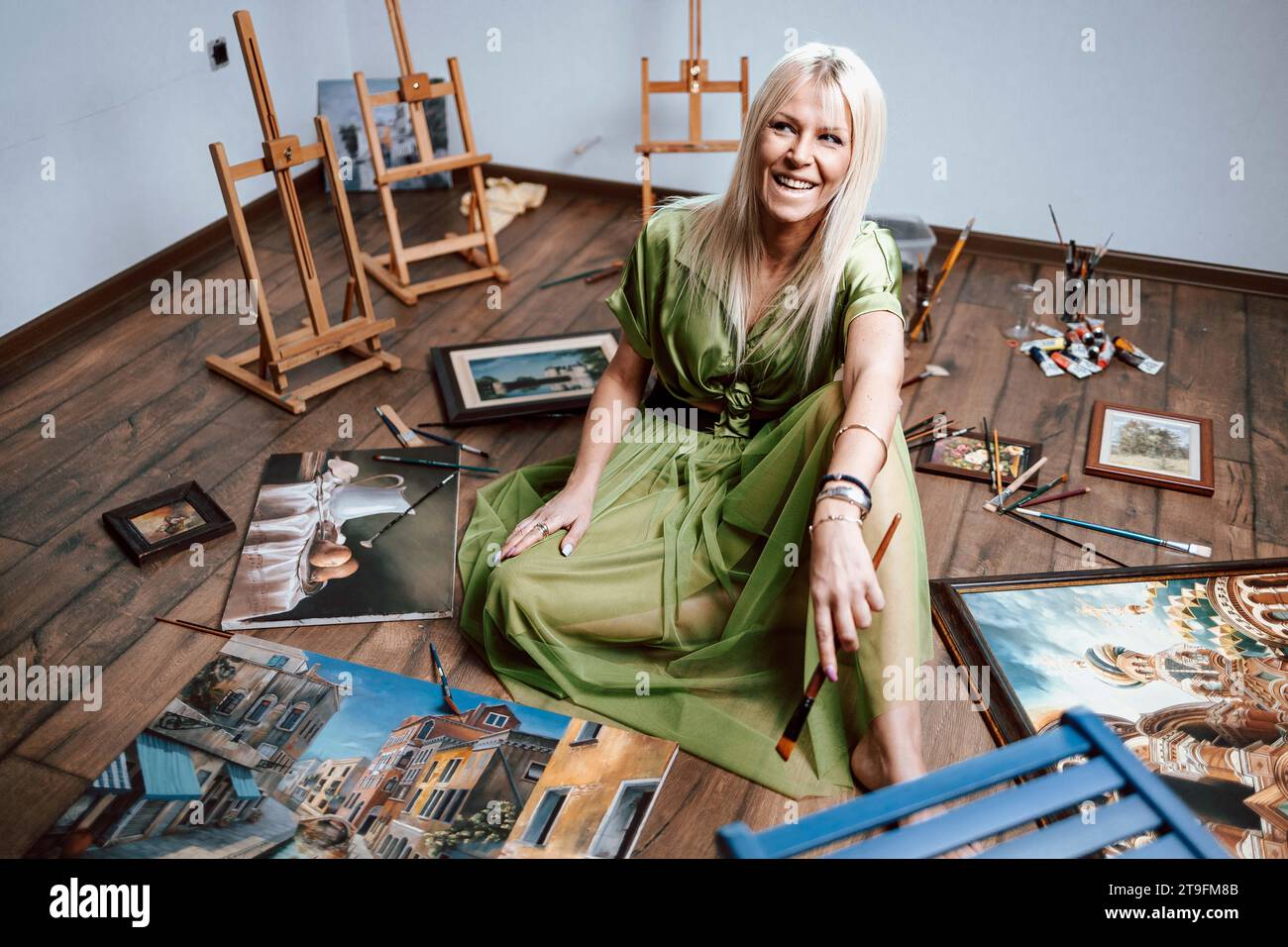 Young blonde woman painter, surrounded by her artwork Stock Photo - Alamy