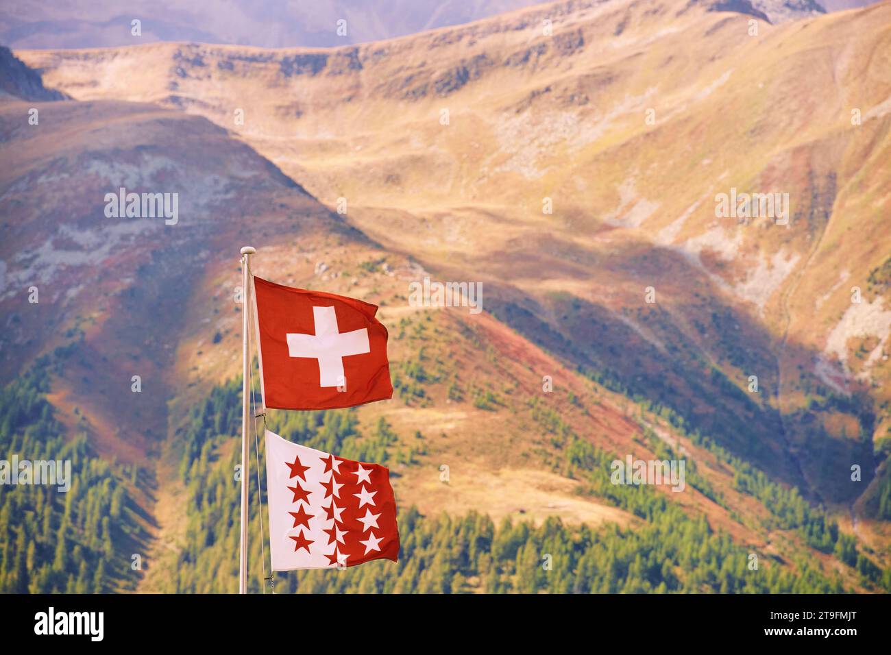 Swiss flag and flag of canton of Valais against swiss alpine mountain ...