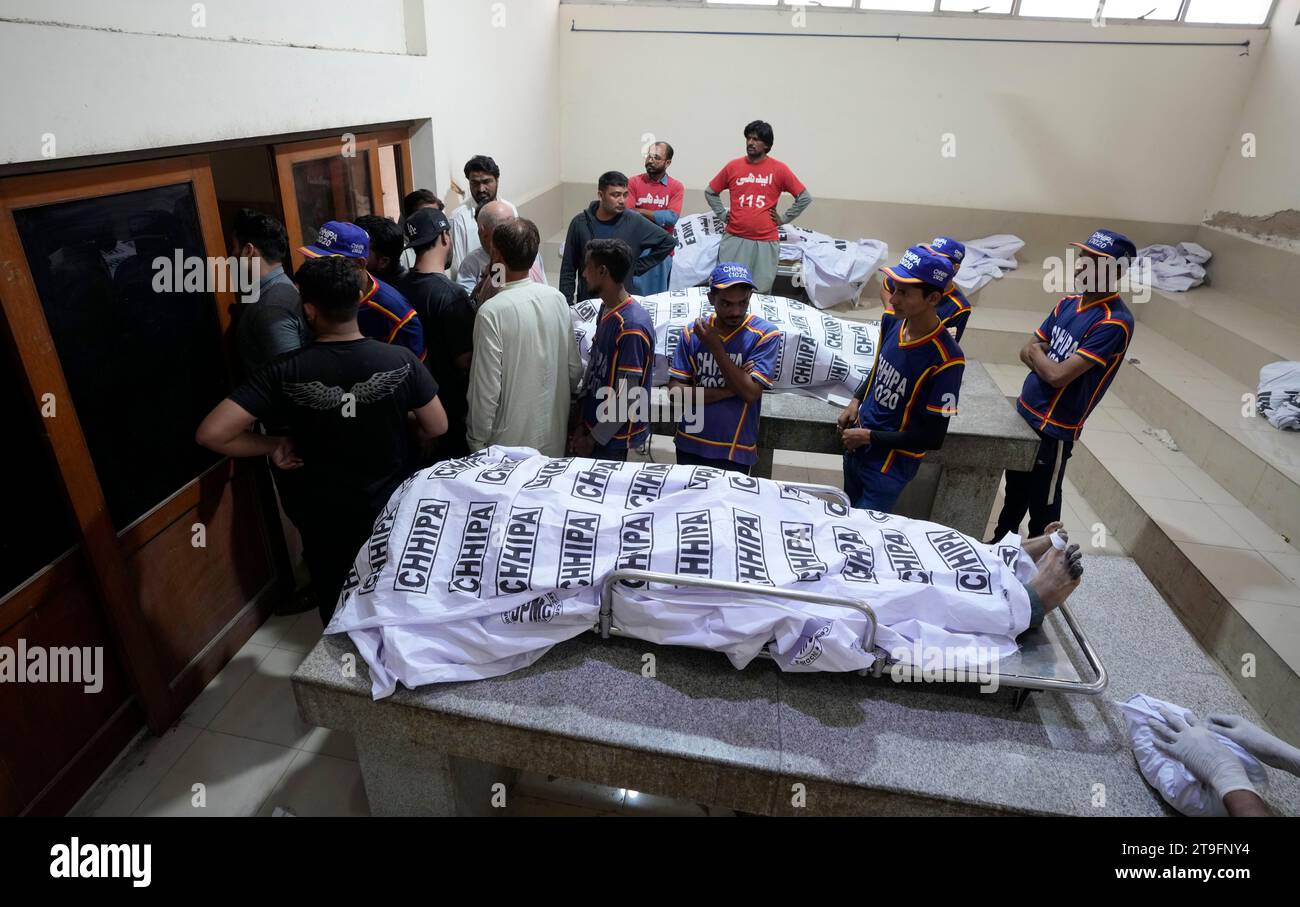 Health workers stand near to the bodies in a morgue after fire in a ...