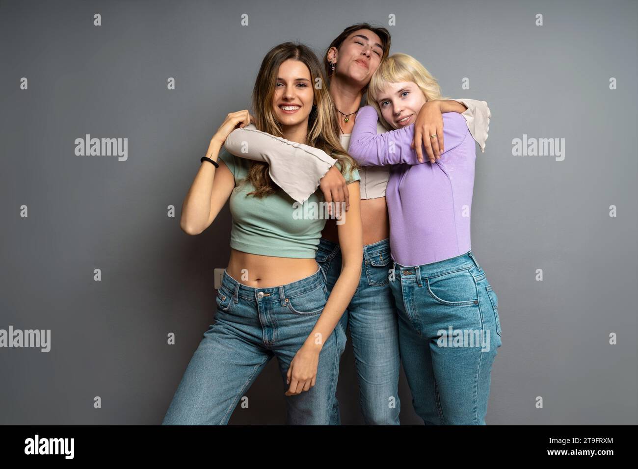 Three diverse women hugging and smiling in a studio setting, portraying ...