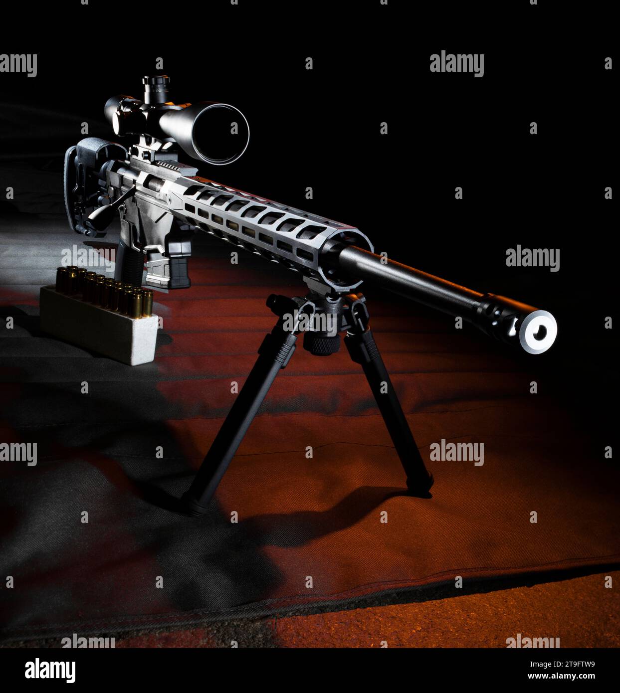 Sniper rifle with orange light from the side with a bipod mounted and ...