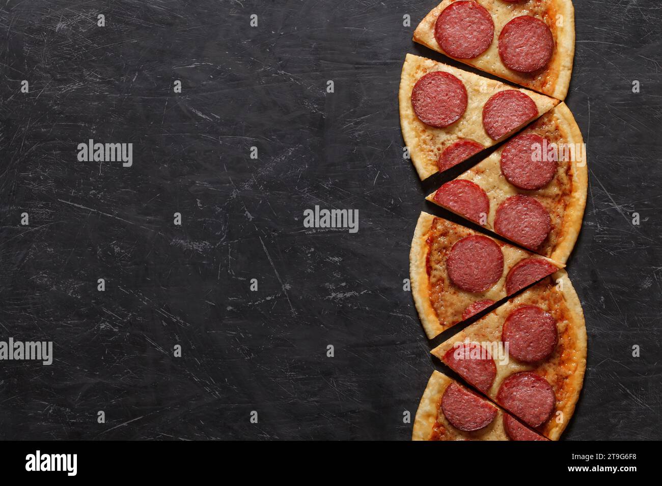 Pepperoni pizza, cut into six pieces, lying in row, top view dark ...