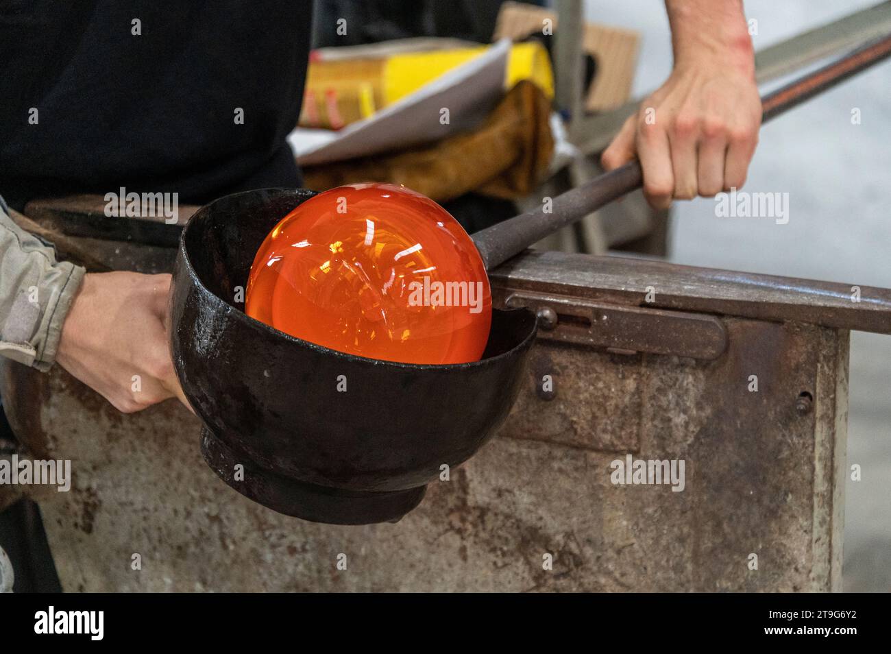 A glassblower skilfully shapes a heated molten mould of clear glass ...