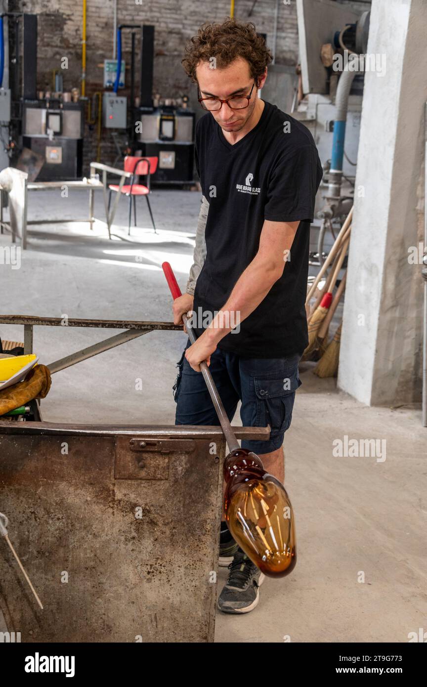 A glassblower skilfully shapes a heated molten mould of clear glass ...