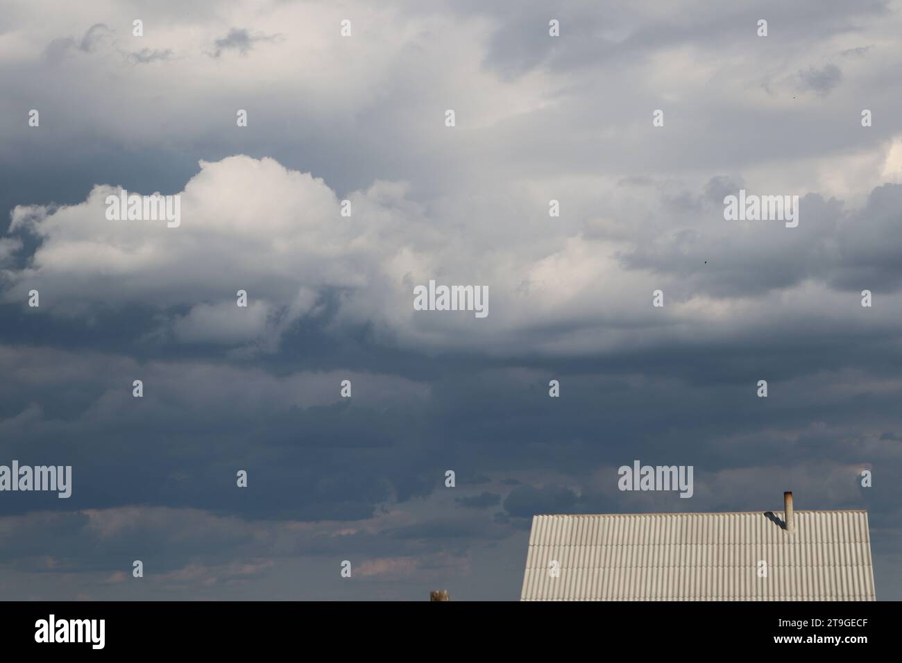 It's raining Dark rain clouds are gathering over the roof of a house in ...