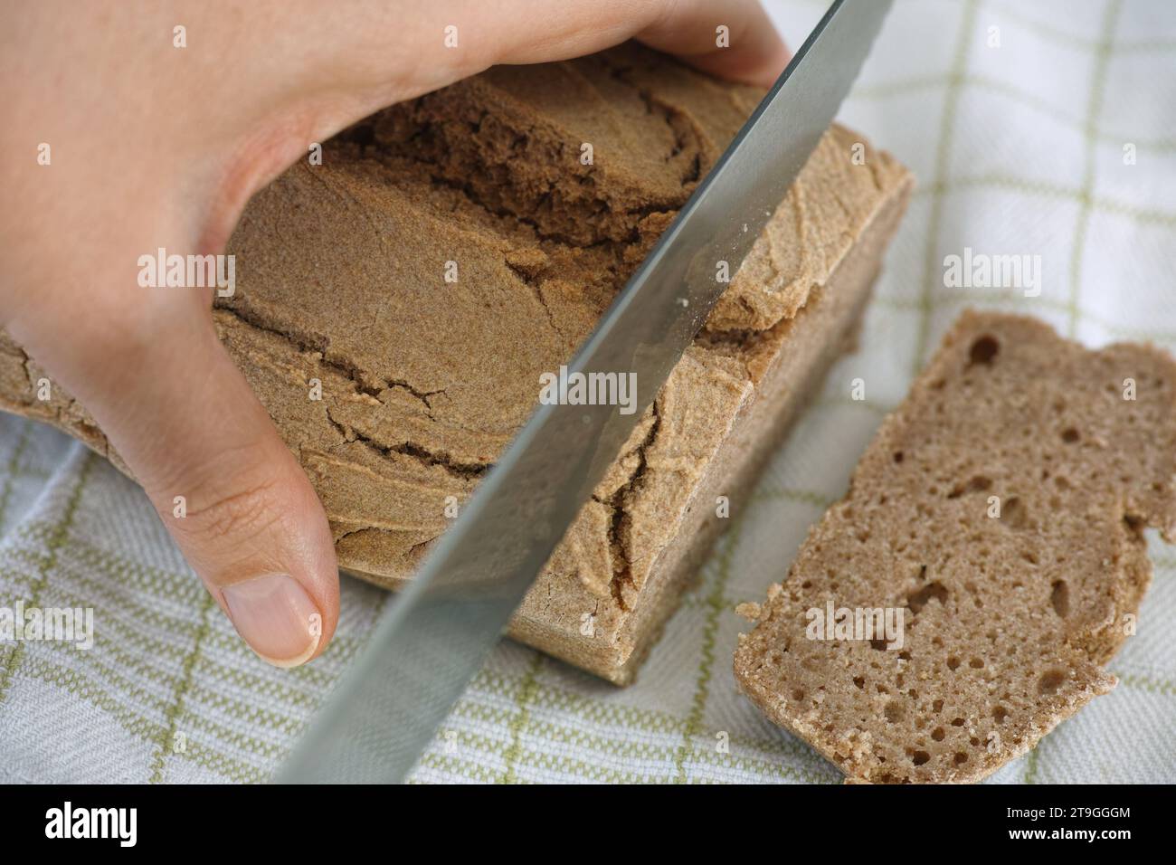 A woman cutting brown gluten free bread. Close up Stock Photo - Alamy
