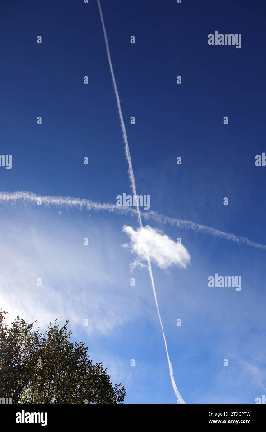 long white trails high in the blue sky crossing a cloud without ...