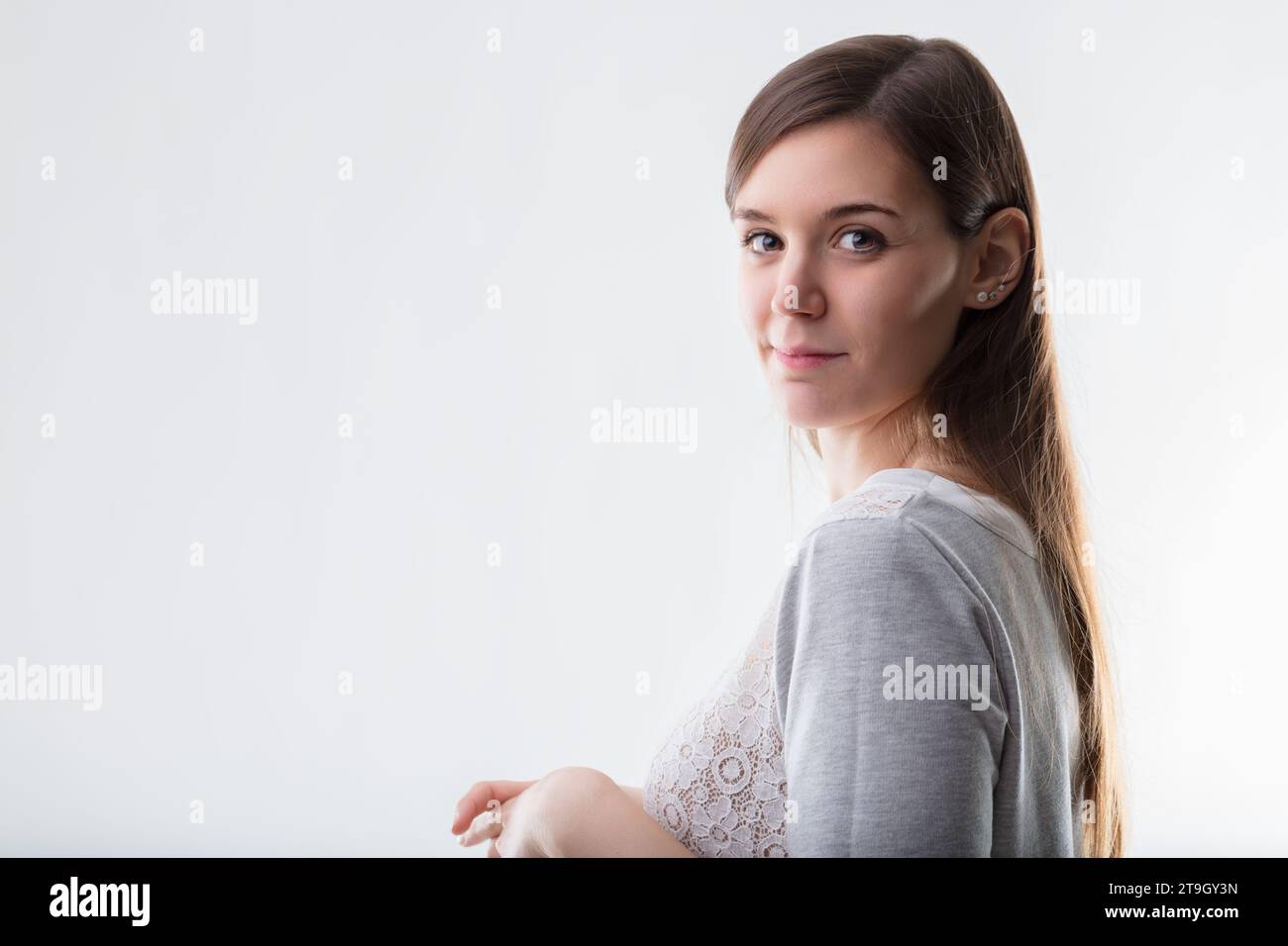 Contemplative young woman in a lace-adorned shirt, offering a glimpse ...