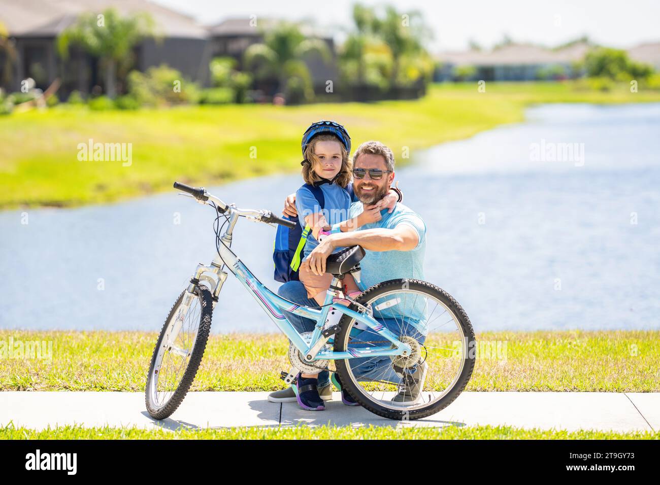dad guiding his son first bike ride. dad and son enjoying fun bike ...