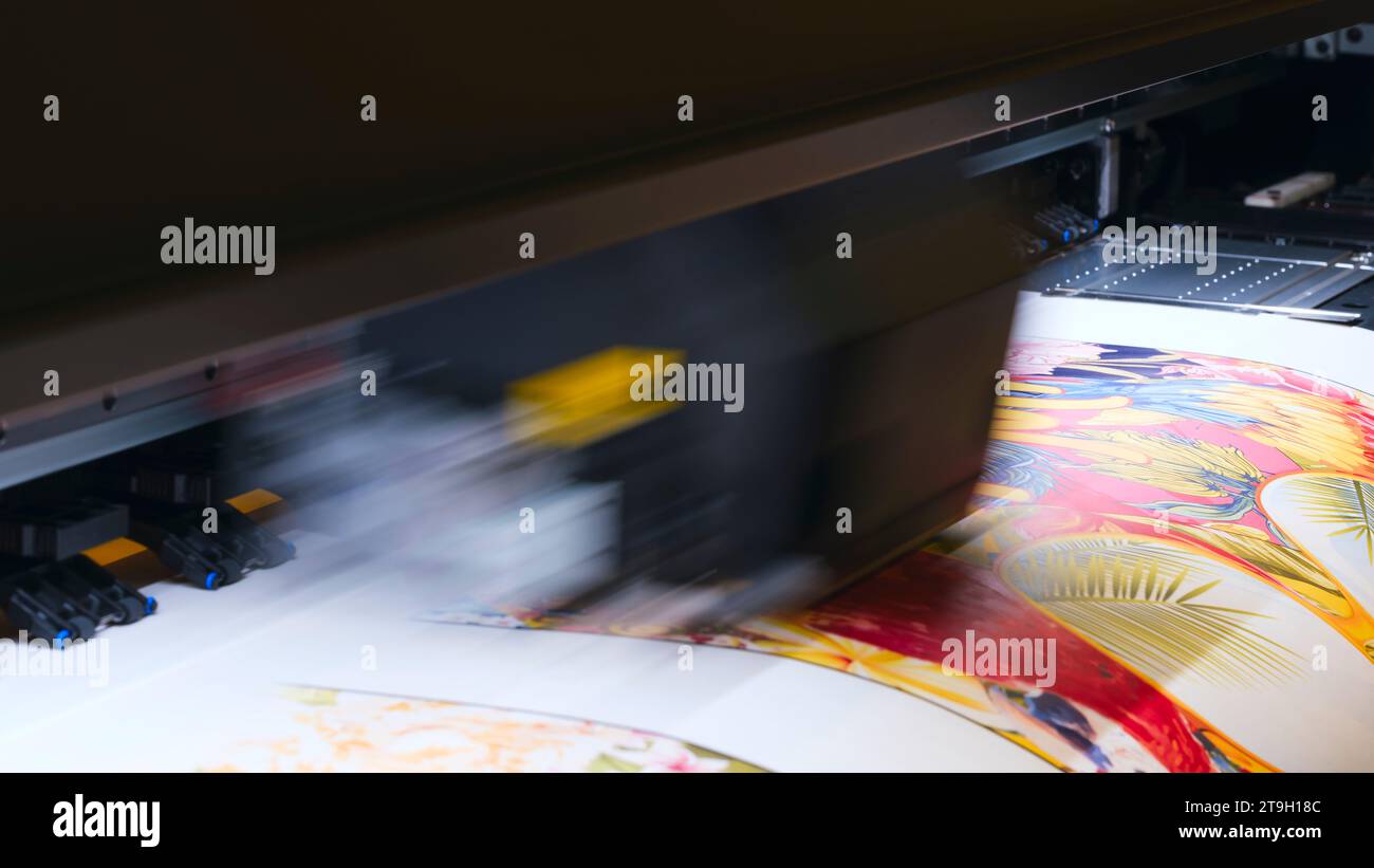 A moving working industrial wide format printer prints a color picture ...