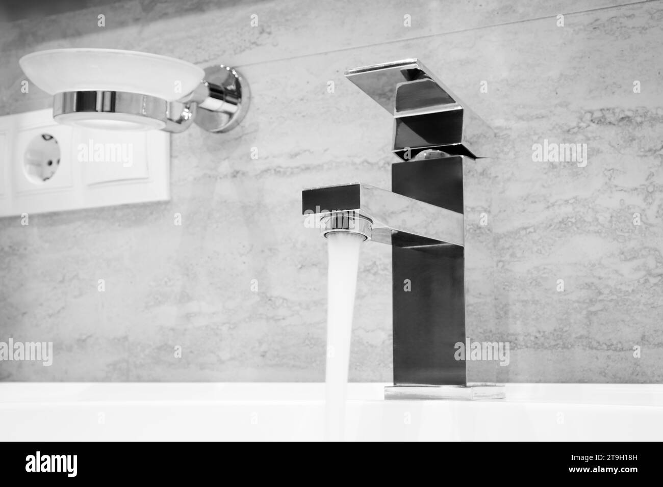 Modern chrome faucet with water flow in gray bathroom interior ...