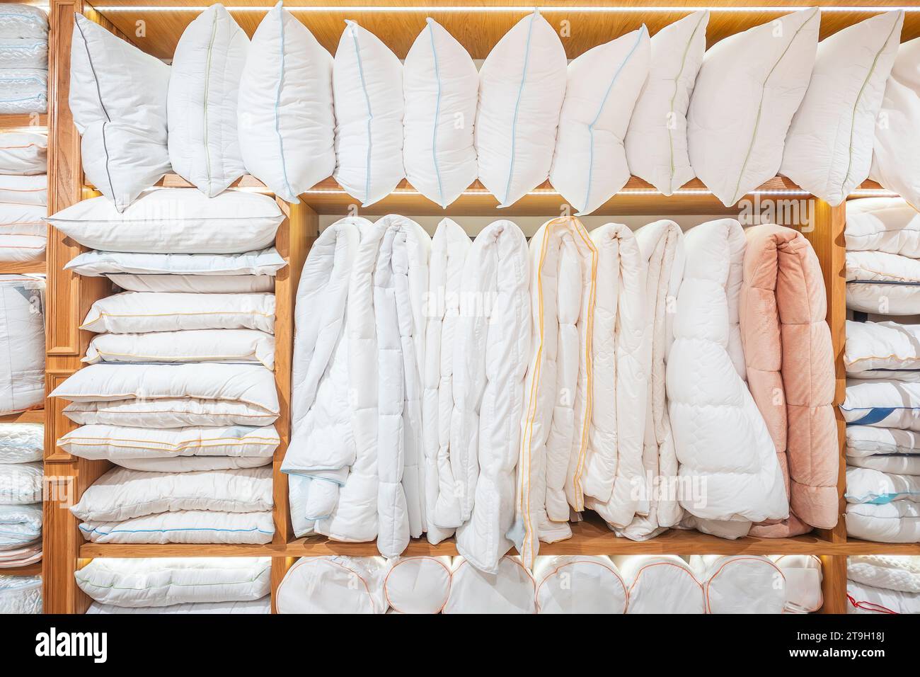 A lot of white bed linen on display in a store on wooden shelves Stock ...