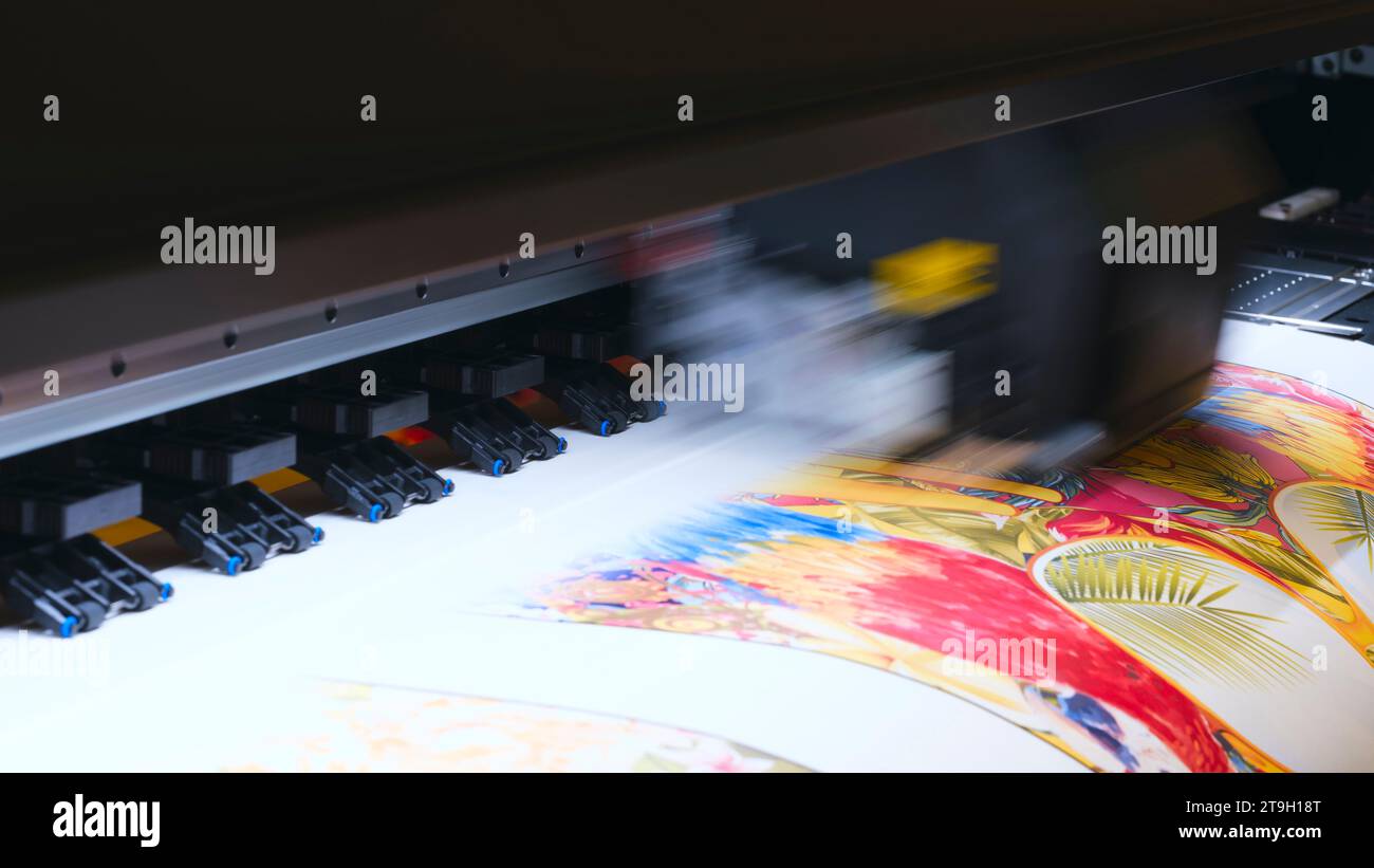 A moving working industrial wide format printer prints a color picture ...