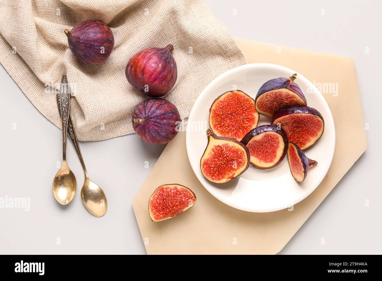 Plate with fresh juicy cut figs and spoons on white background Stock ...