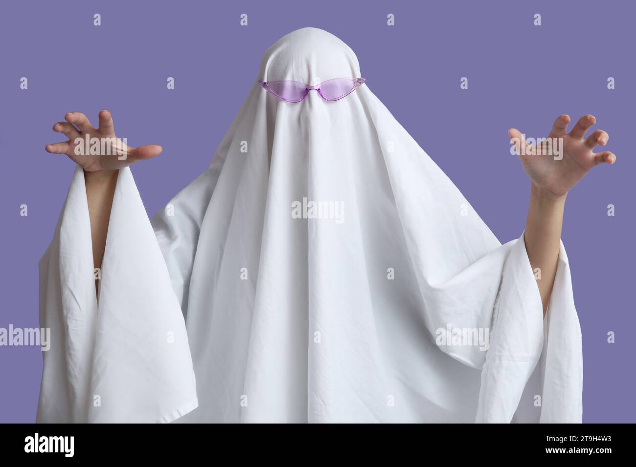 Woman in Halloween costume of ghost and sunglasses on lilac background ...