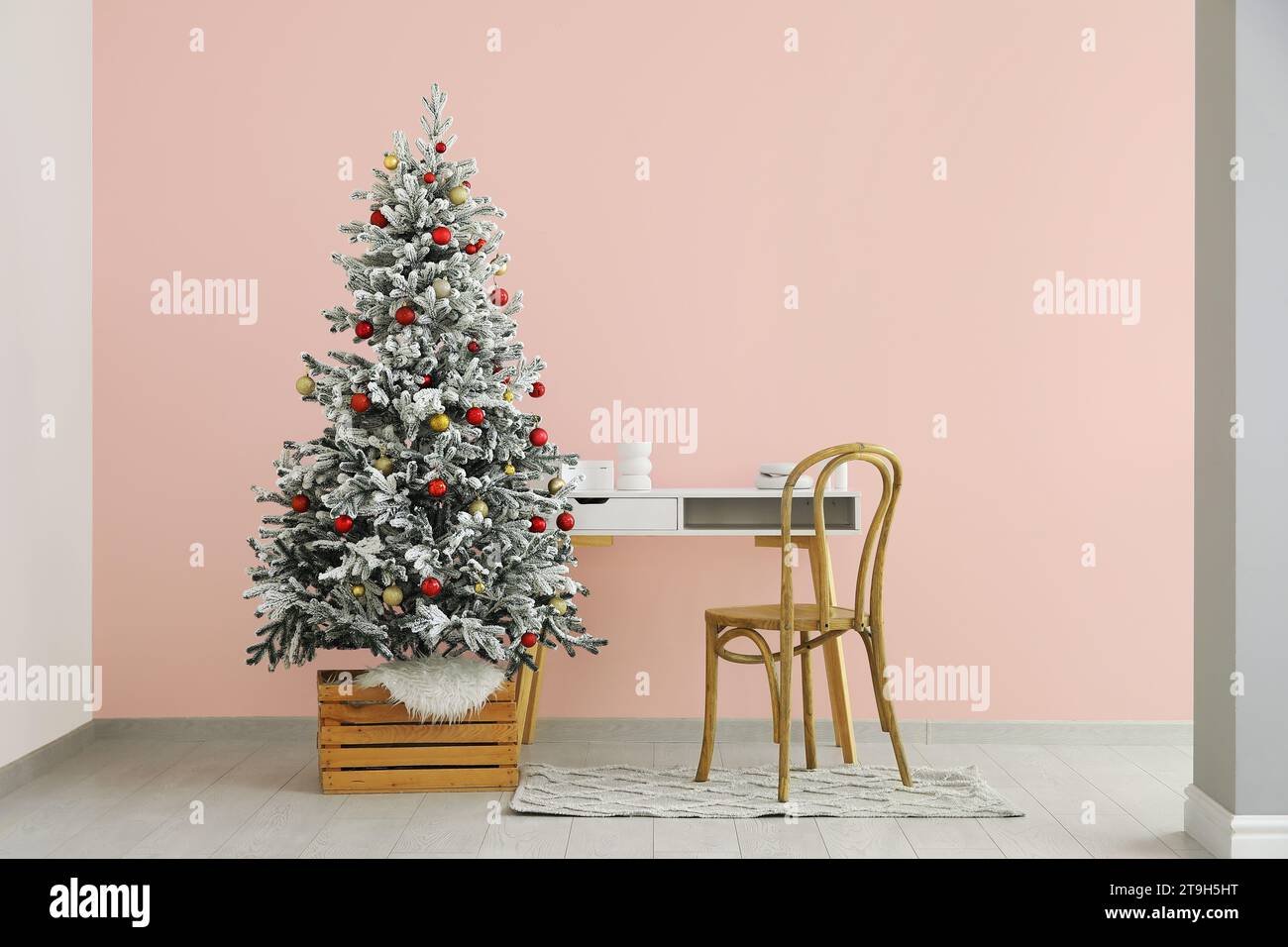 Beautiful Christmas tree with desk and chair near pink wall Stock Photo ...