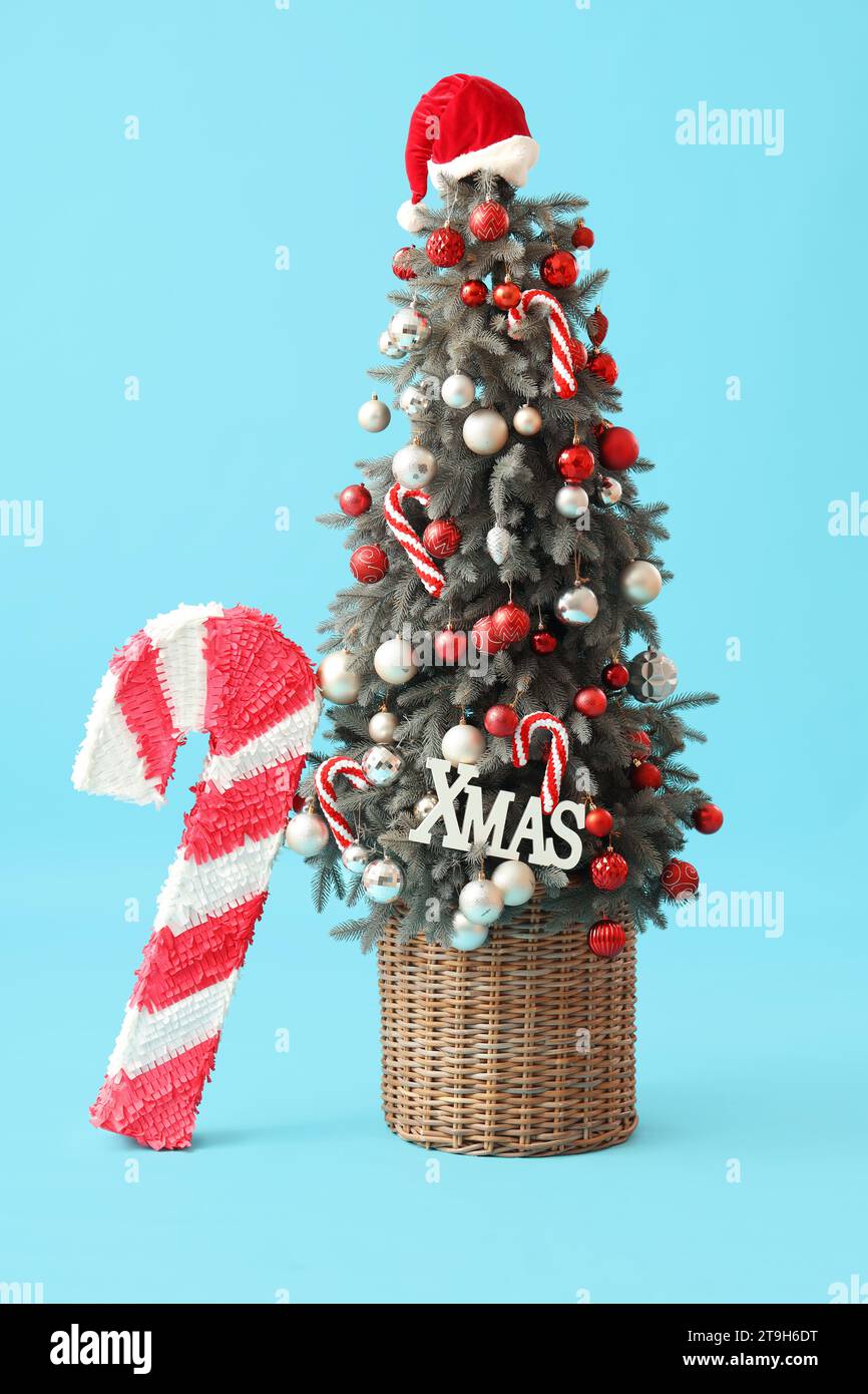 Beautiful Christmas tree and candy cane pinata on color background ...