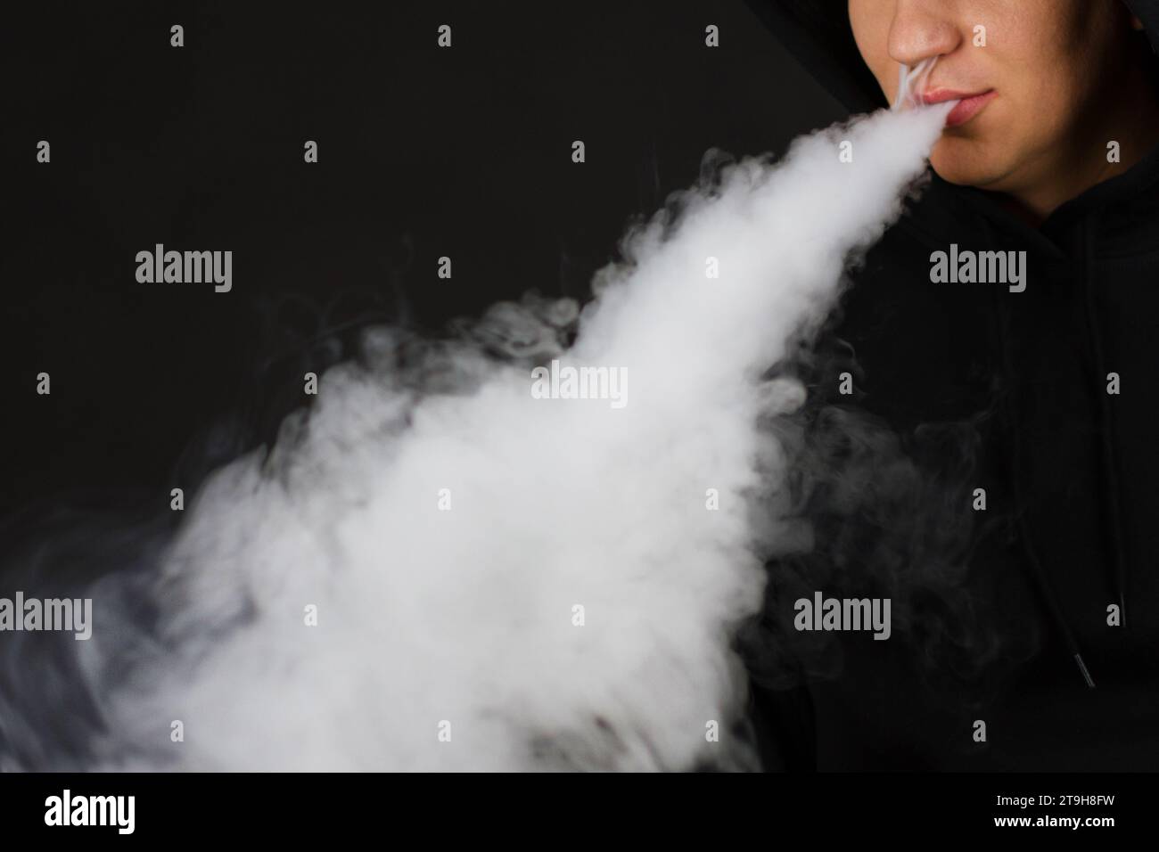 vaping man holding a mod cloud of vapor Black background isolated ...