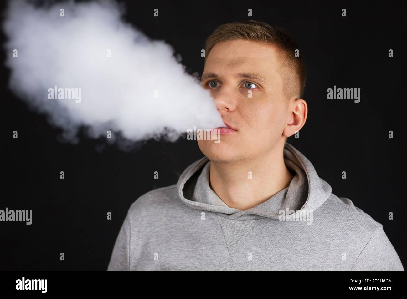 The man smoke an electronic cigarette on the dark background, Men in ...