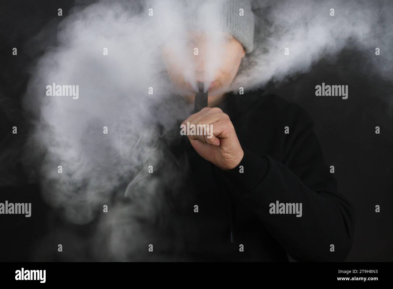 The man smoke an electronic cigarette on the dark background, Men in ...