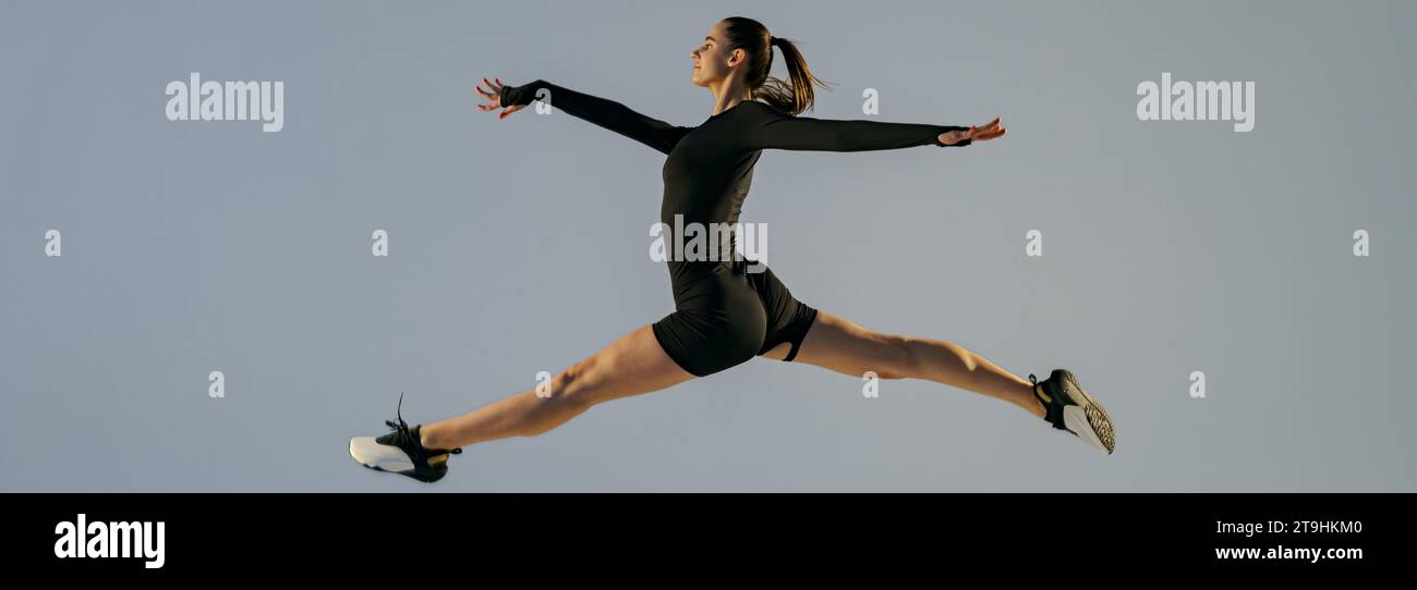 Sporty girl jumping doing split leap in air with joyful expression ...