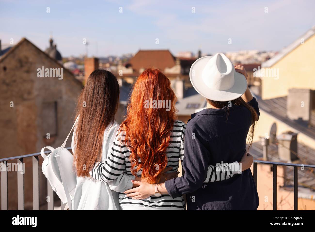 Friends enjoying of cityscape on balcony, back view Stock Photo - Alamy