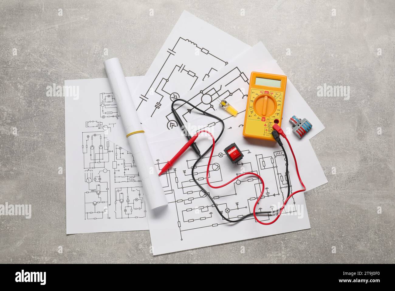 Wiring diagrams, digital multimeter and connectors on grey table, flat ...