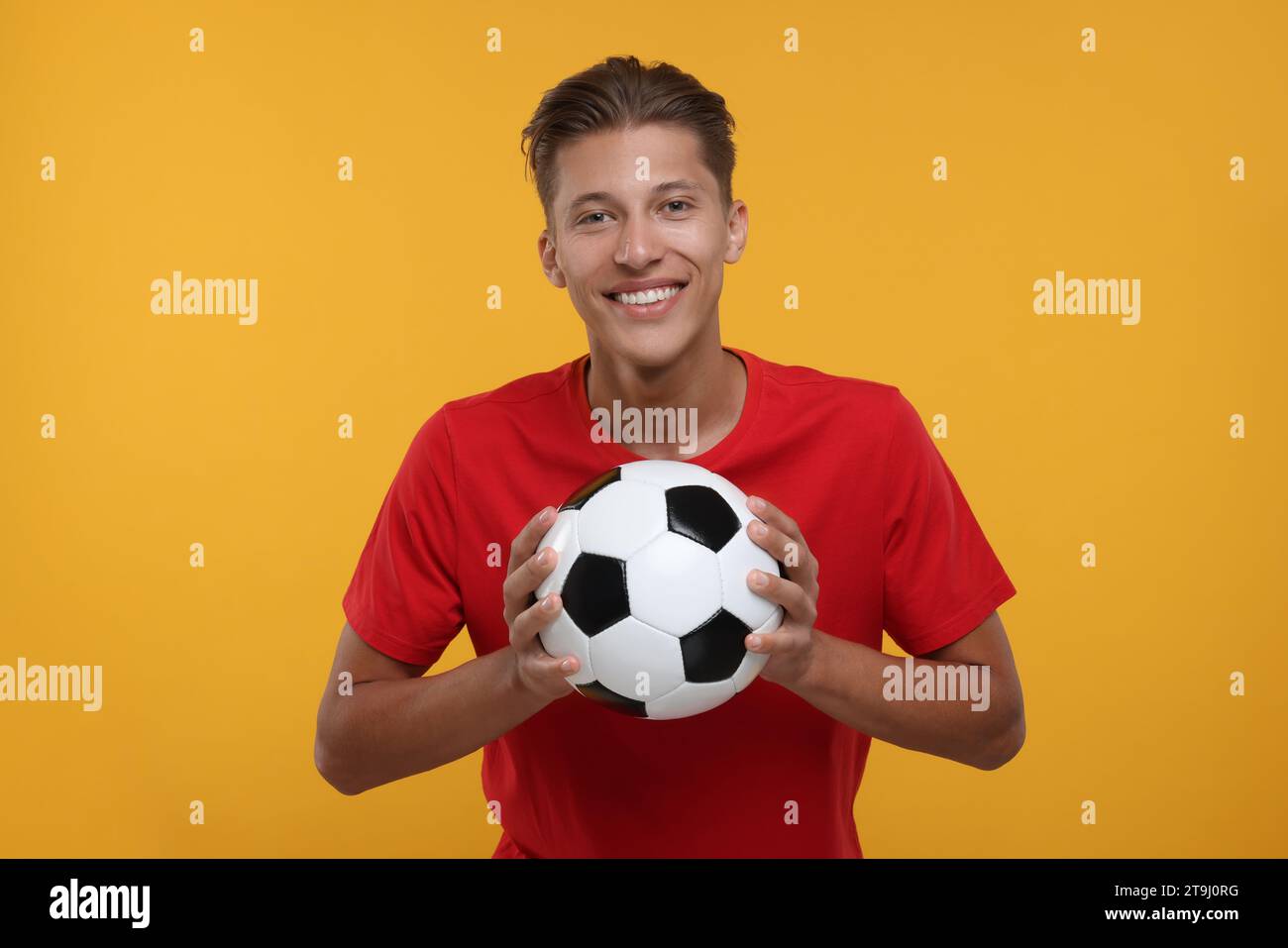 Happy sports fan with soccer ball on orange background Stock Photo - Alamy