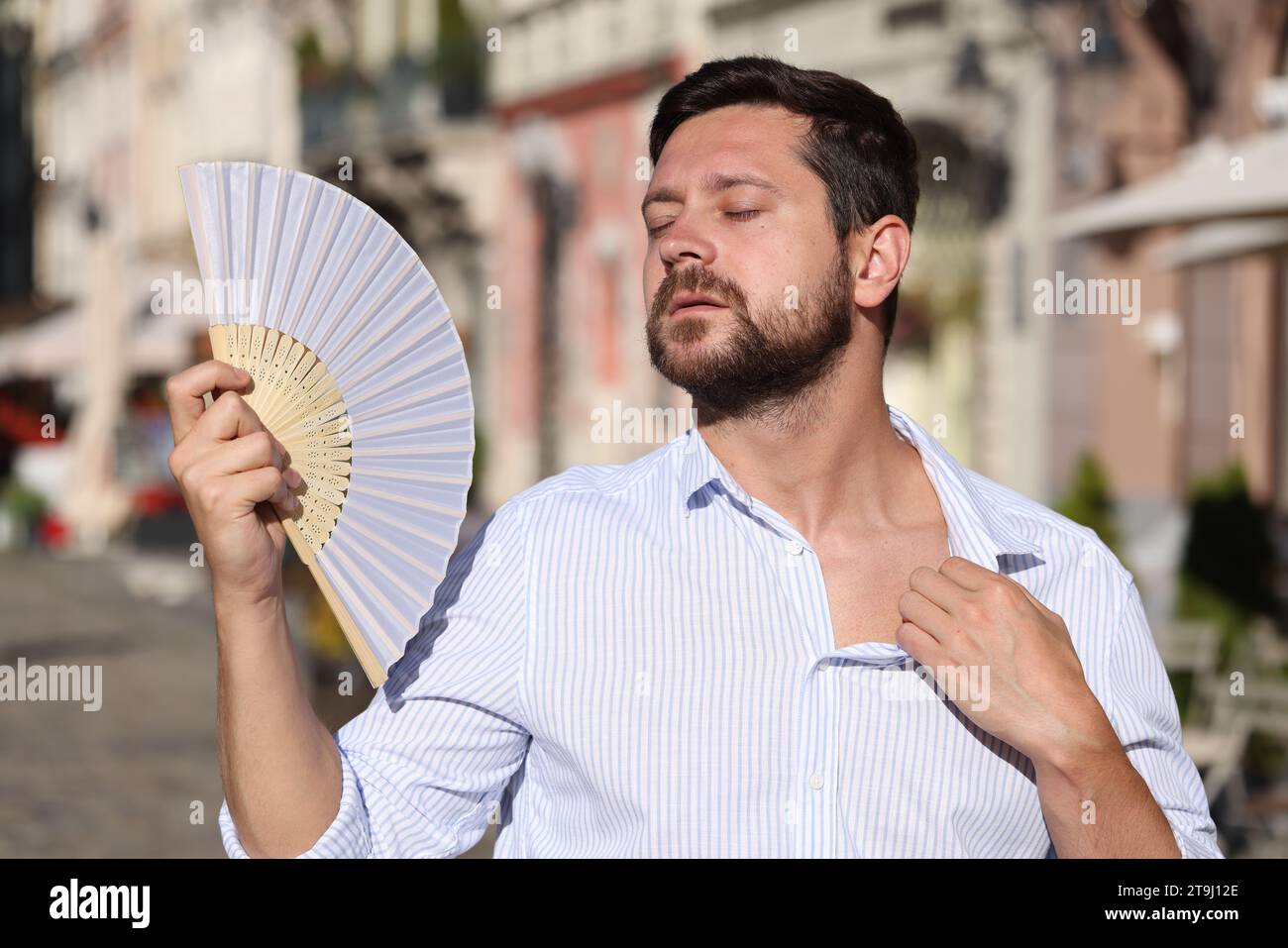 Man with hand fan suffering from heat outdoors Stock Photo - Alamy