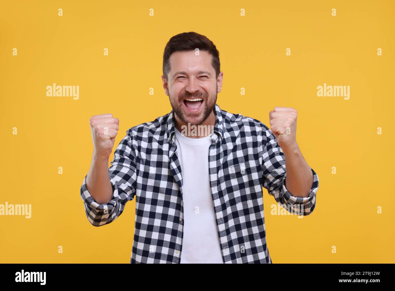 Emotional sports fan celebrating on yellow background Stock Photo - Alamy