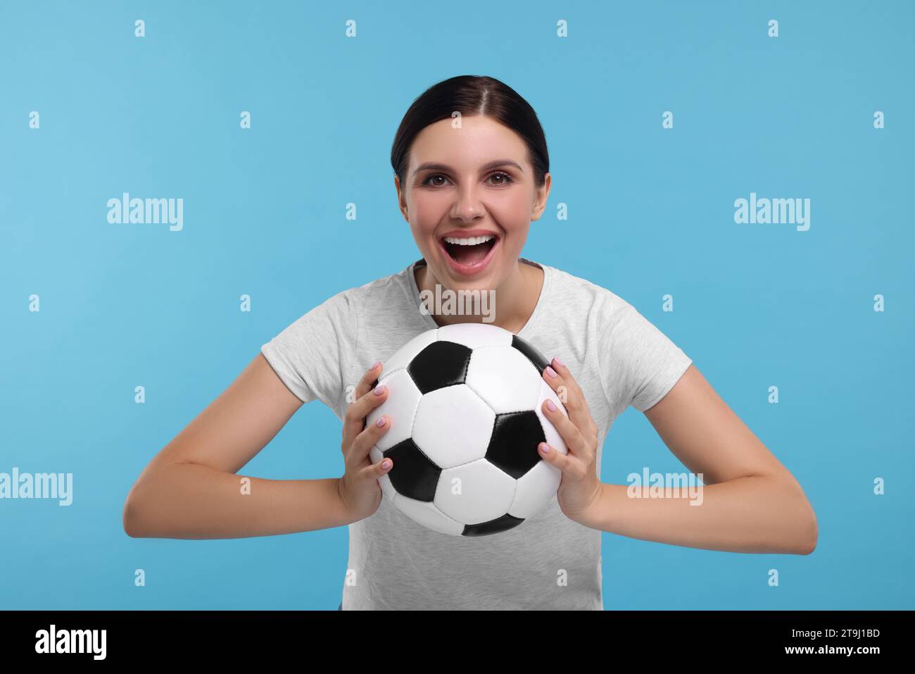 Emotional sports fan with soccer ball on light blue background Stock ...