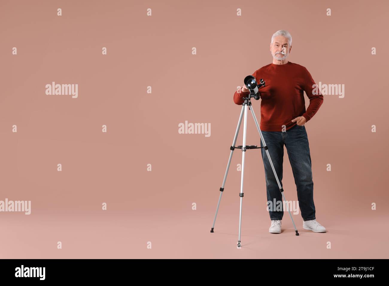 Senior astronomer with telescope on brown background. Space for text ...
