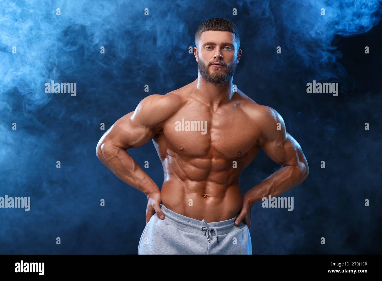 Young bodybuilder with muscular body in smoke on color background Stock ...