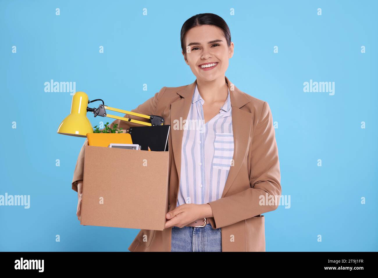 Happy unemployed woman with box of personal office belongings on light ...