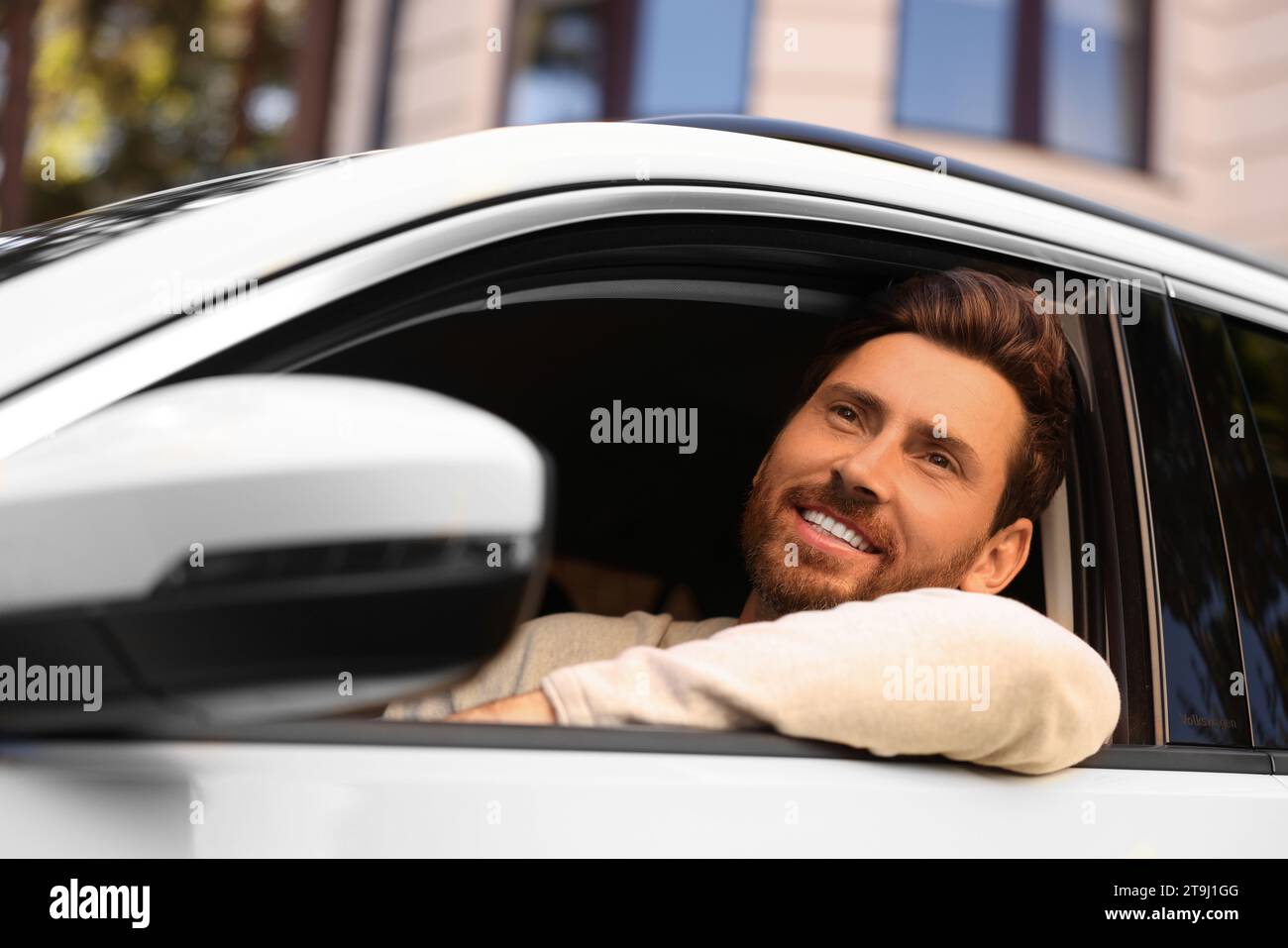 Happy man looking out of car window on city street, view from outside ...