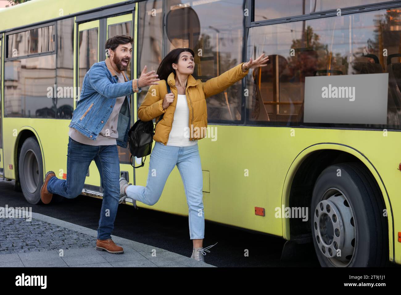 Being late. Worried couple running towards bus outdoors, space for text ...