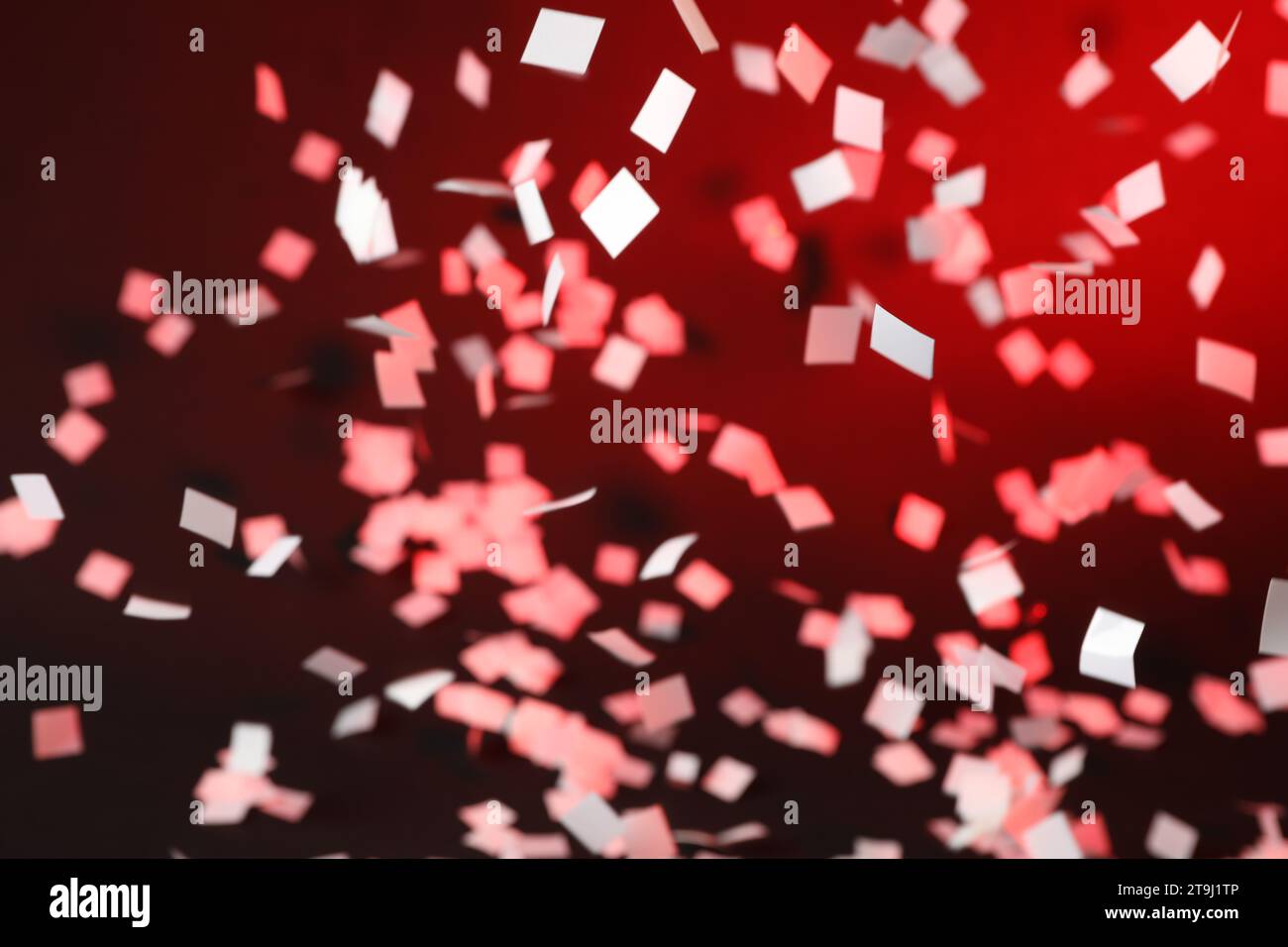 White confetti falling down on dark red background Stock Photo - Alamy