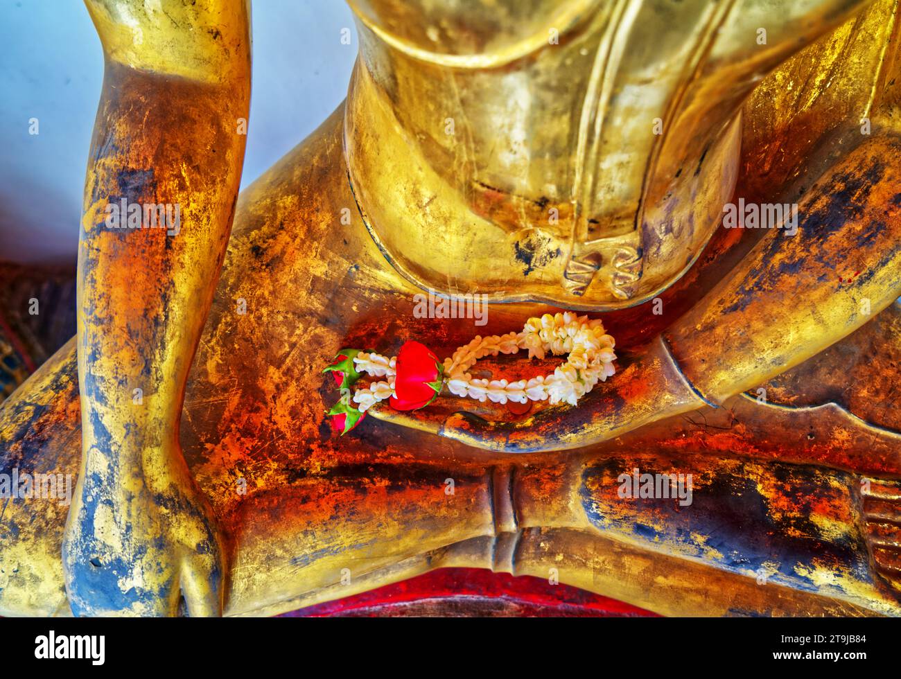 Close-up small garland on an ancient golden Buddha's hand in a temple ...