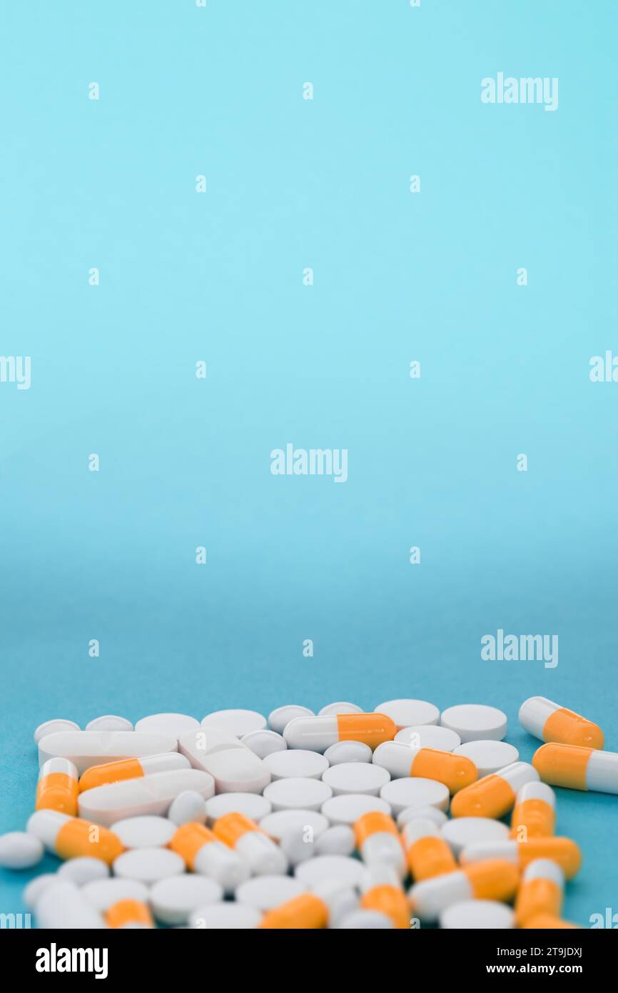 A group of antibiotic pill capsules on blue background with copy space ...