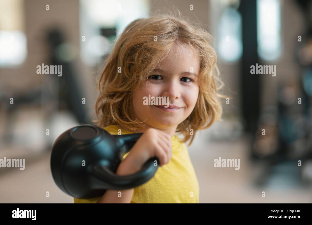 Kid workout kid in gym. Kid raising a kettlebell. Cute child training ...