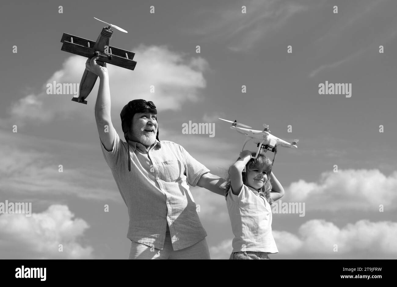 Grandfather and grandson hold plane and drone quad copter against sky ...