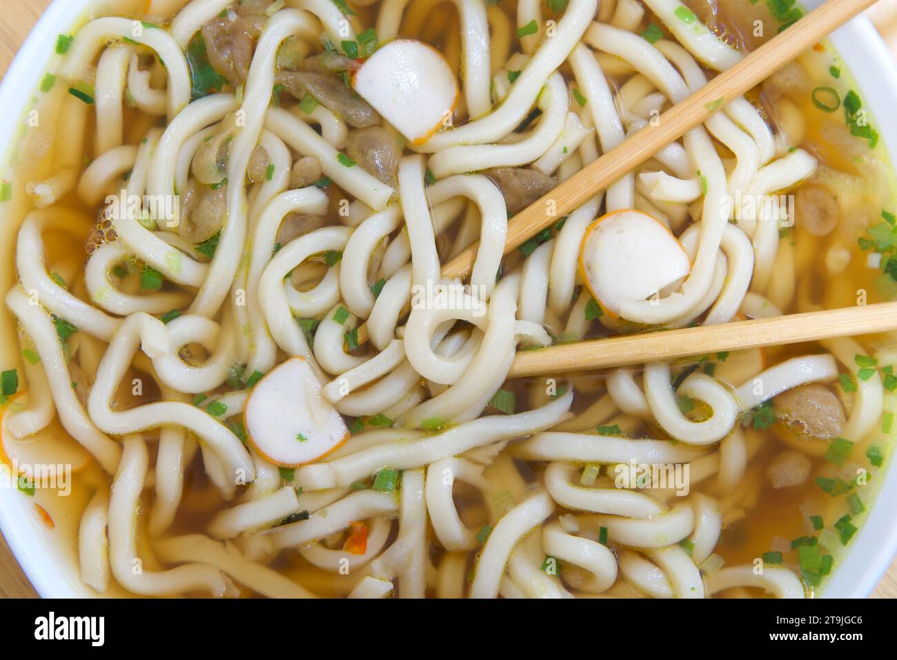 Close up top view flat lay of one bowl of udon noodles in beef broth ...
