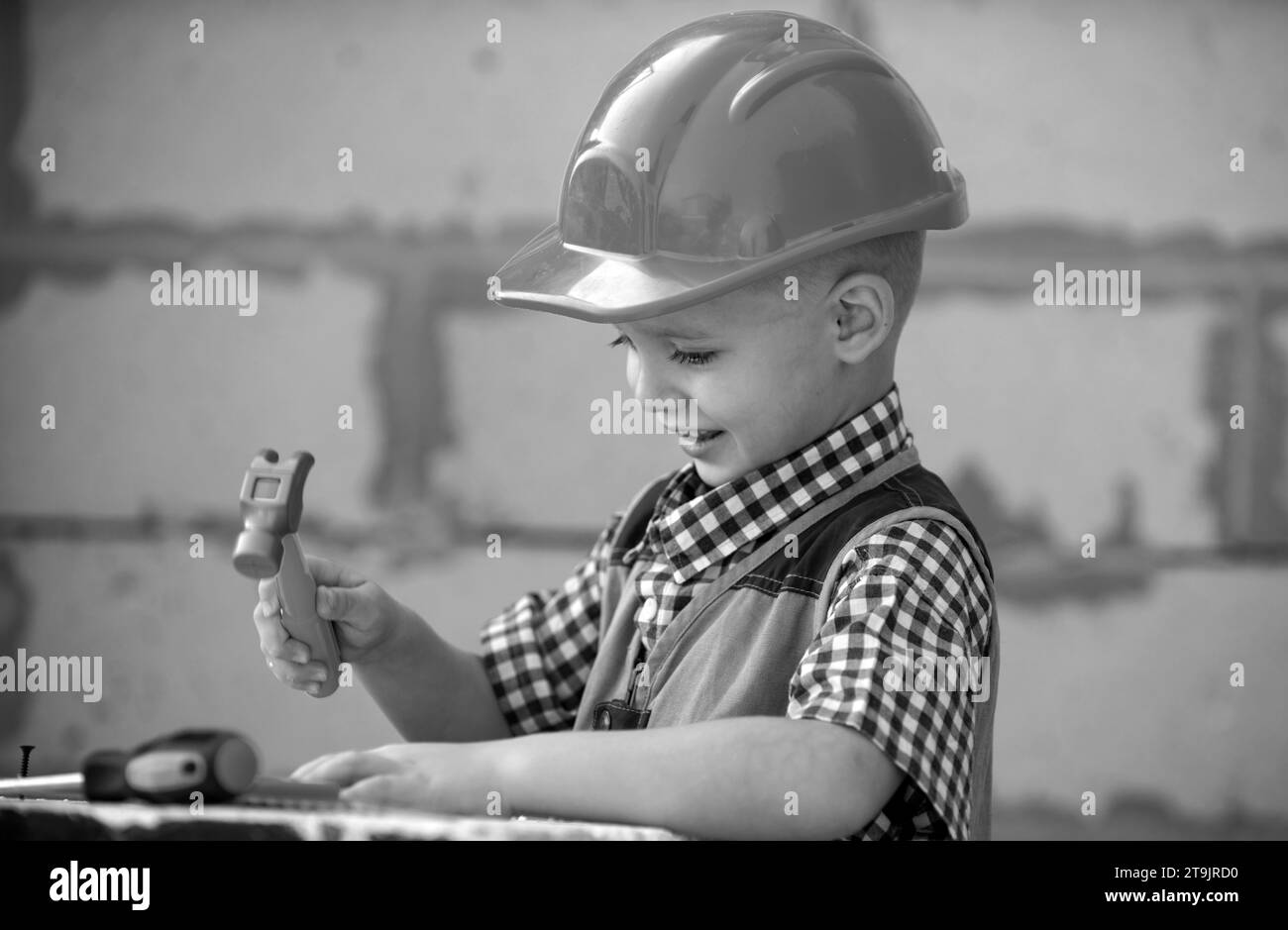 Kid in hard hat holding hammer. Little child helping with toy tools on ...