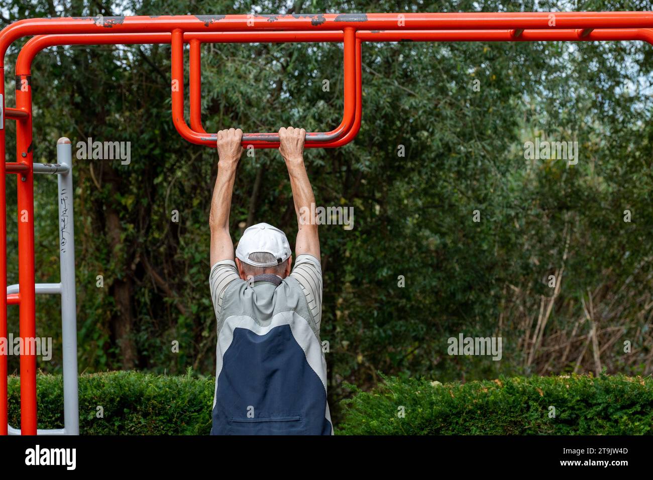 Old caucasian man with white cap, holding on red metal handle grip ...