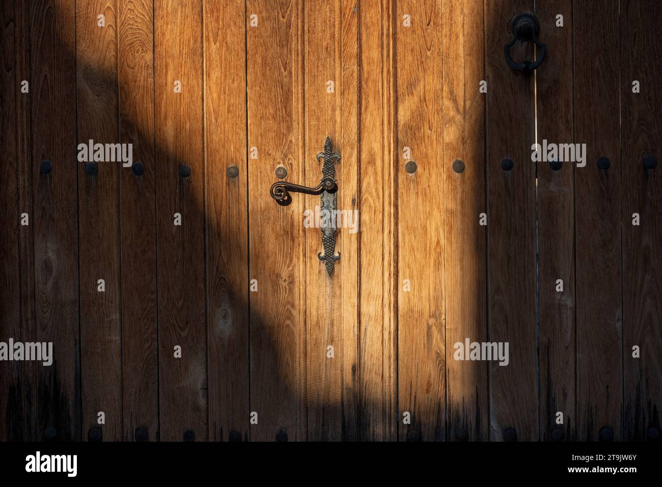 Old wooden brown door illuminated by the sun. Light and shadow. Metal ...